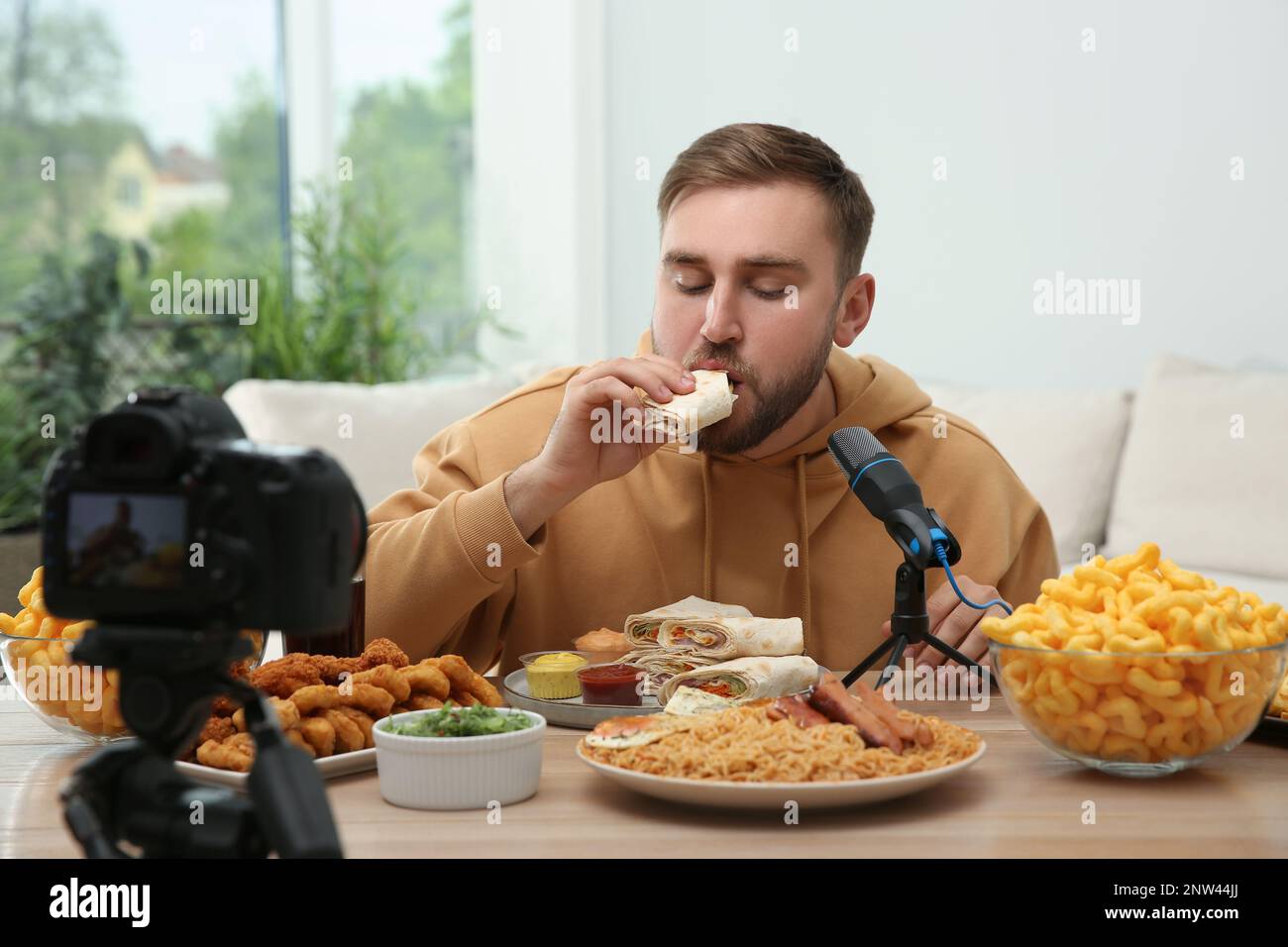 Food blogger recording eating show on camera in room. Mukbang vlog ...