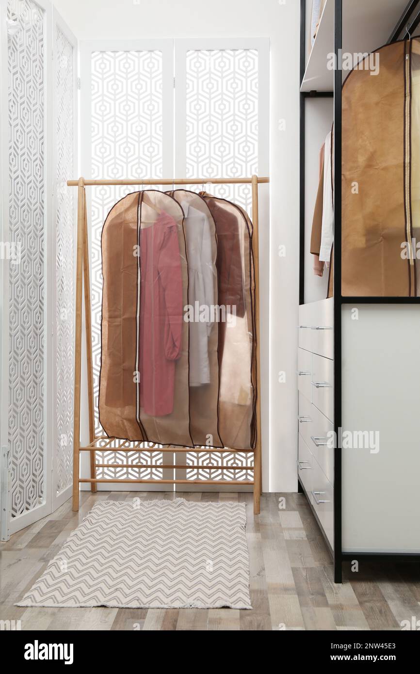 Garment bags with clothes on rack in dressing room Stock Photo - Alamy
