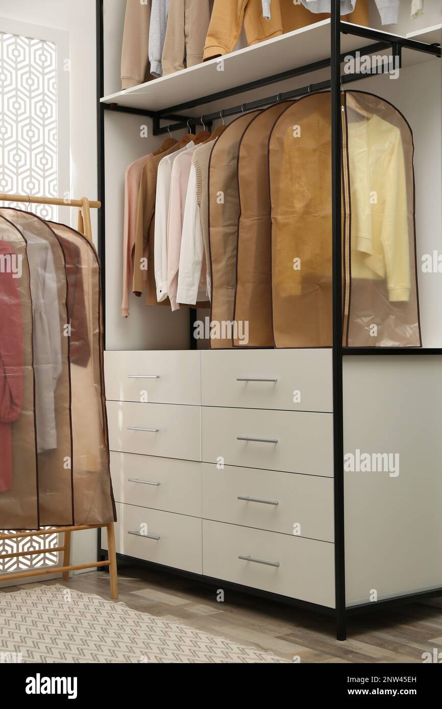 Garment bags with clothes on rack in dressing room Stock Photo - Alamy