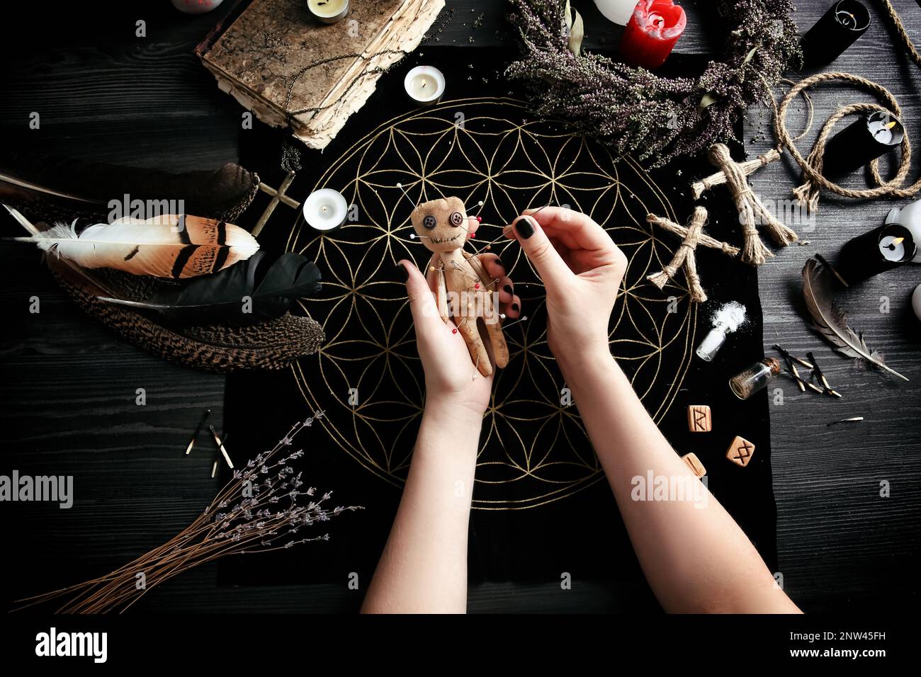 Woman stabbing voodoo doll with needle at table, closeup. Curse ...