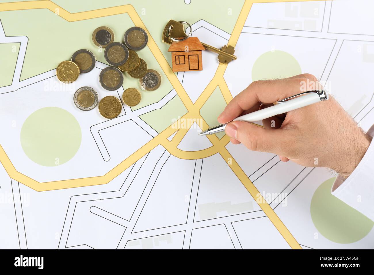 Cartographer with house key and money drawing cadastral map, closeup ...