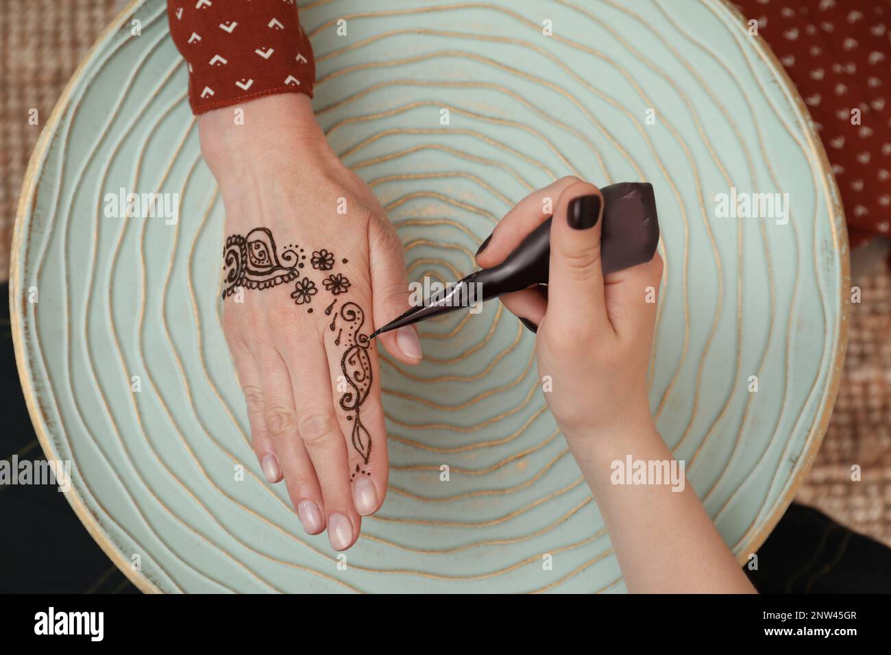 Professional mehndi master making henna tattoo at table, top view Stock ...