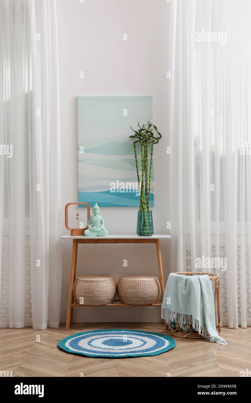 Console table with bamboo and Buddha statue near light wall indoors ...