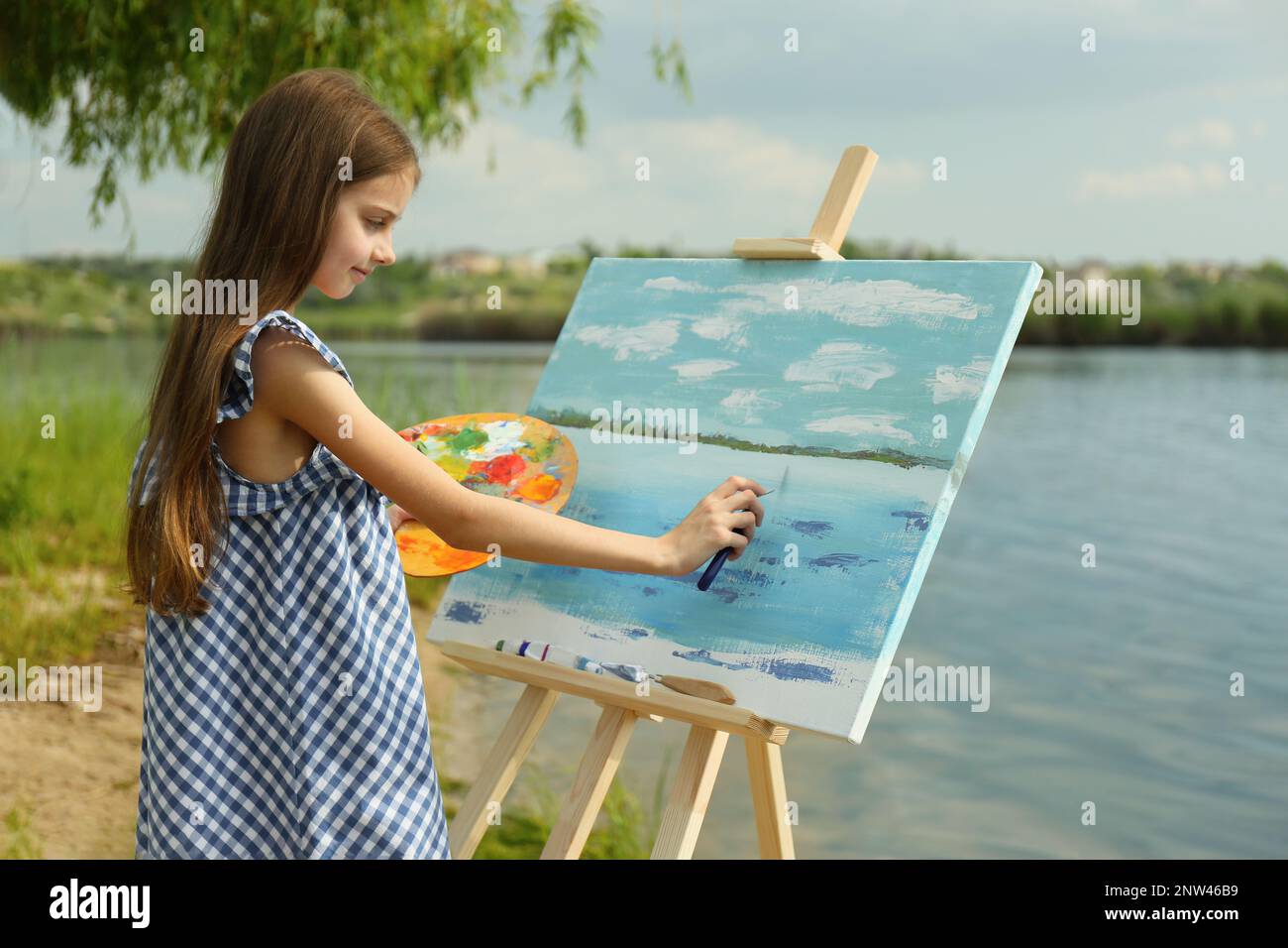 Little girl painting scenery on easel near lake Stock Photo - Alamy