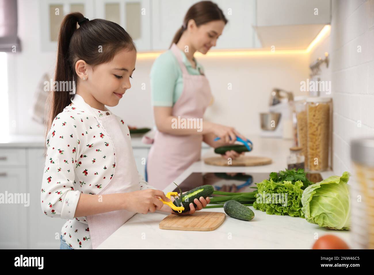 Mother and daughter peeling vegetables at kitchen counter Stock Photo ...