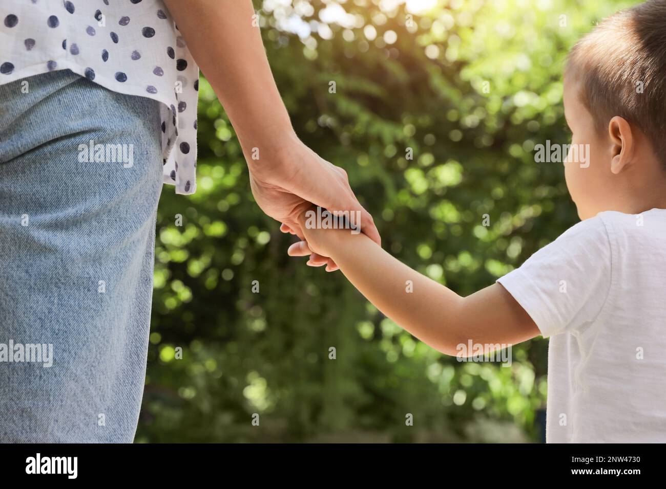 Mom and her child holding hands in park, closeup Stock Photo - Alamy