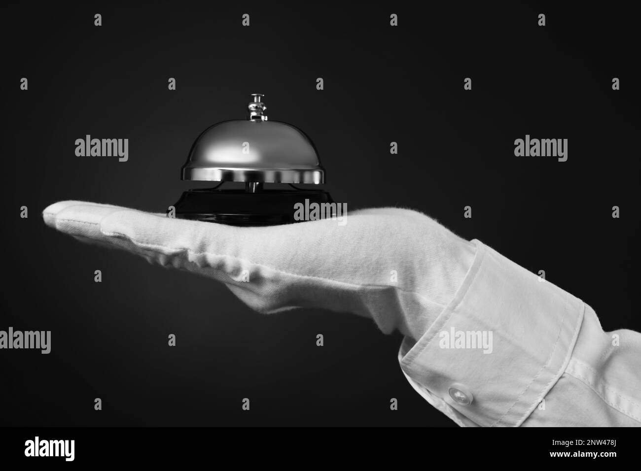 Butler holding service bell on black background, closeup Stock Photo ...