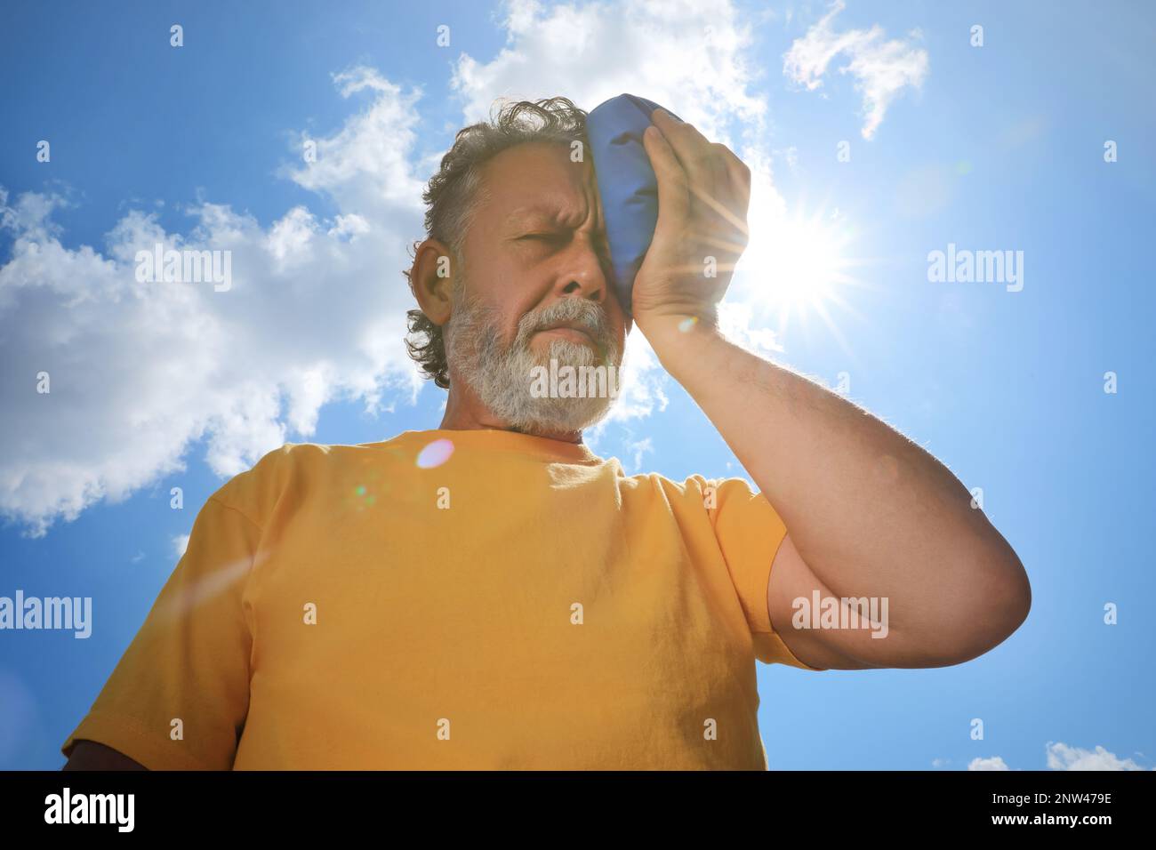 Senior man with cold pack suffering from heat stroke outdoors, low ...