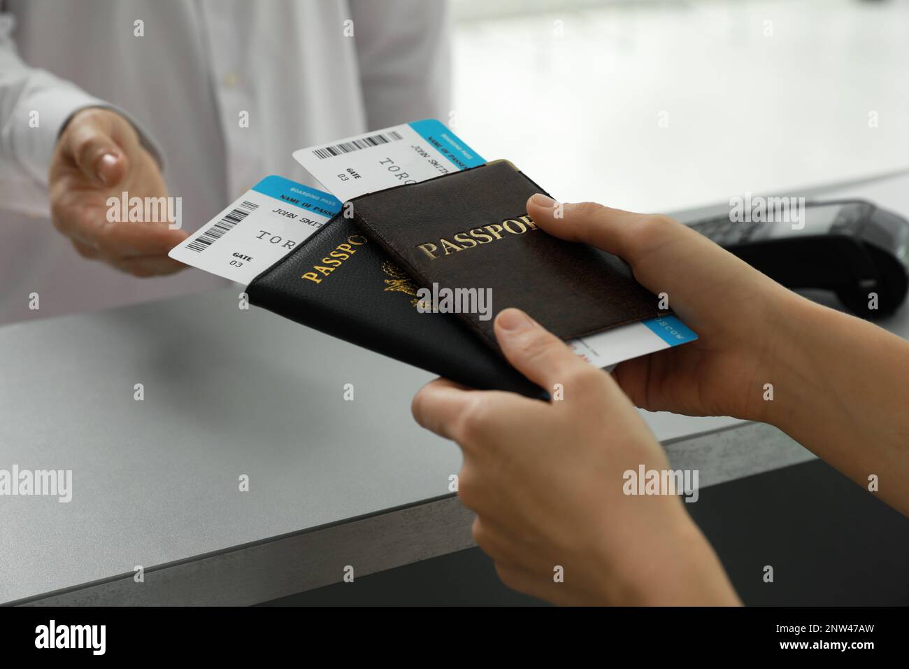 Agent giving passports and tickets to man at check-in desk in airport ...