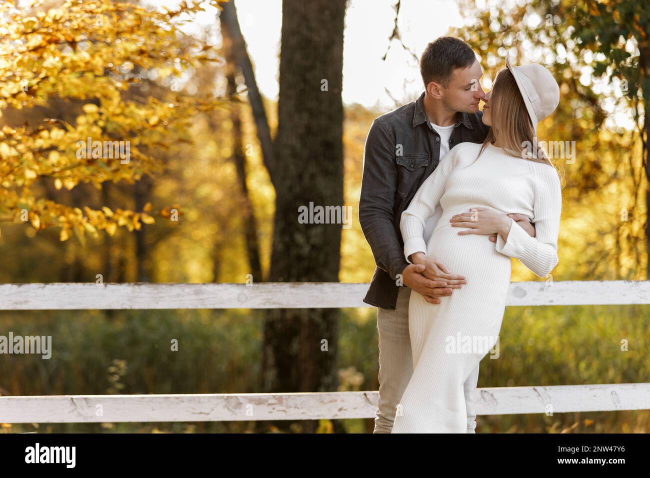 Happy stylish pregnant woman and man hugs, kiss, touches belly and ...