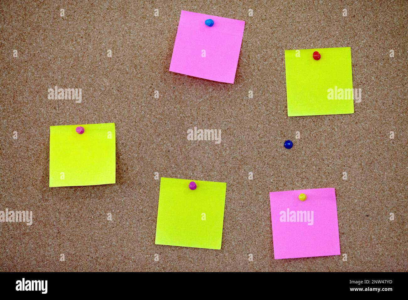 Full frame bulletin board with five blank post-it pinned with thumbtack ...