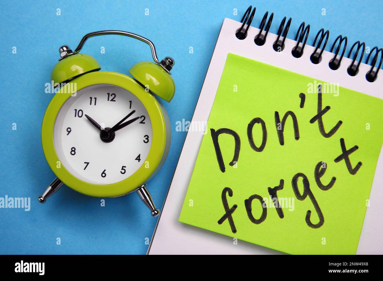 Alarm clock, notebook and reminder note with text Don't forget on light ...