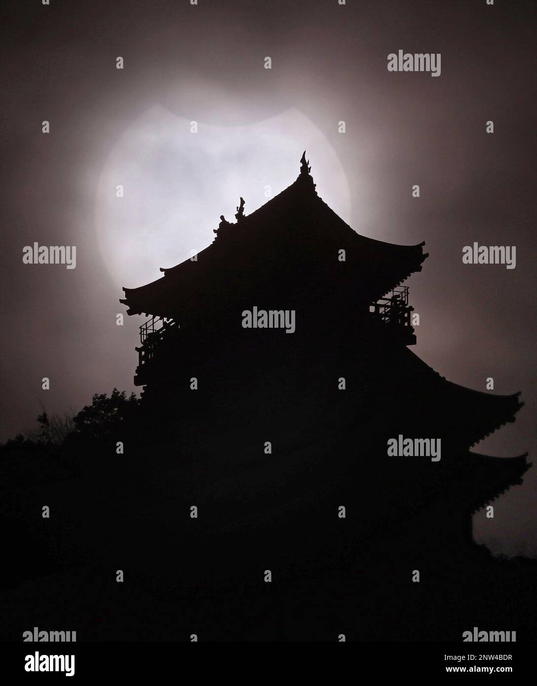 A partial solar eclipse is observed in the background of Gifu Castle in ...
