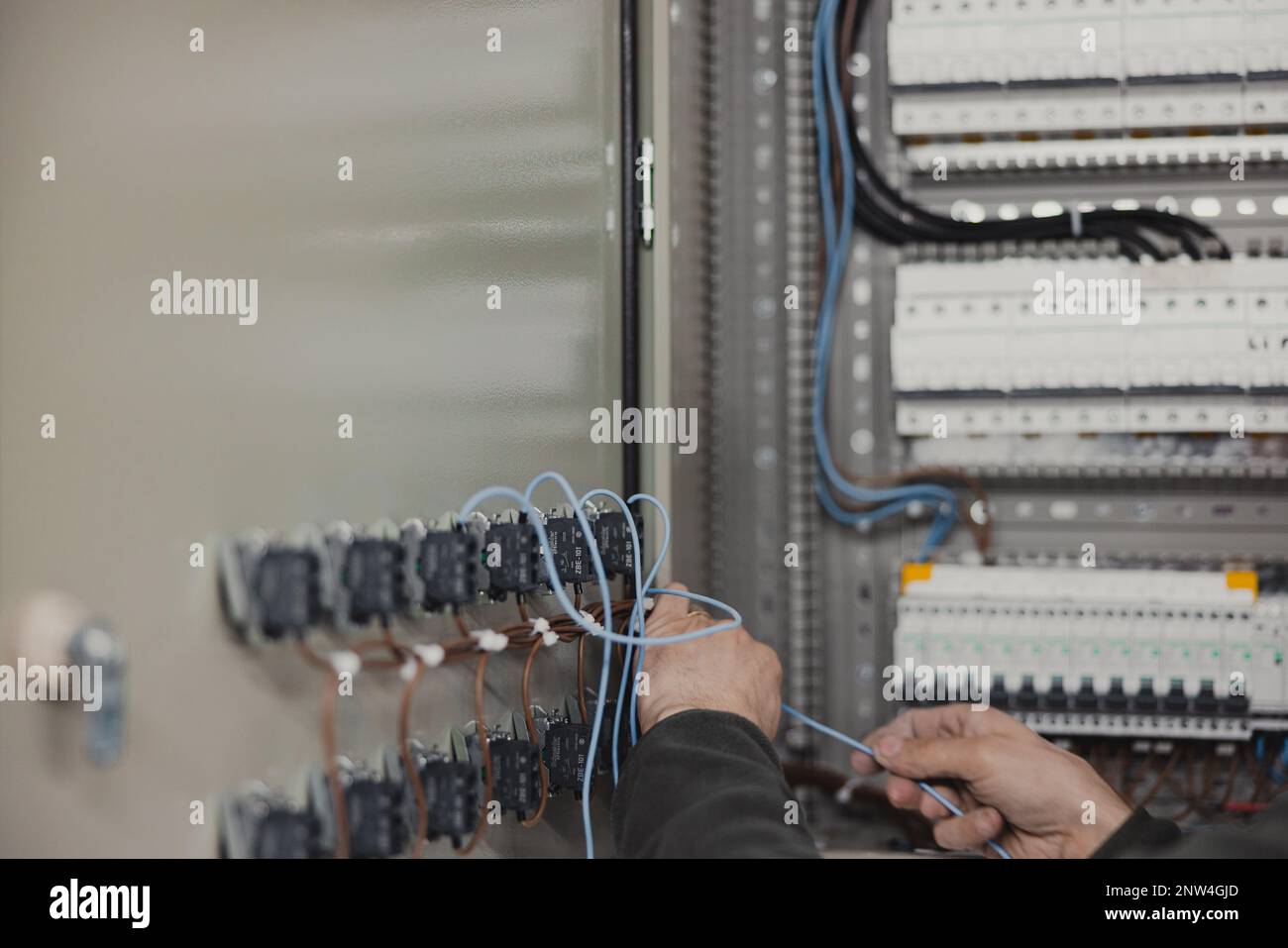 A close-up of electrician hands working on switches in control room ...
