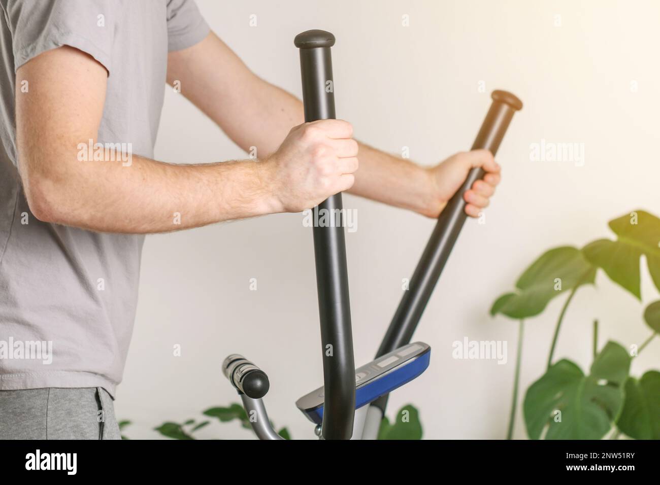 A man trains on an Elliptical Machine. Sports trainer at home in the ...