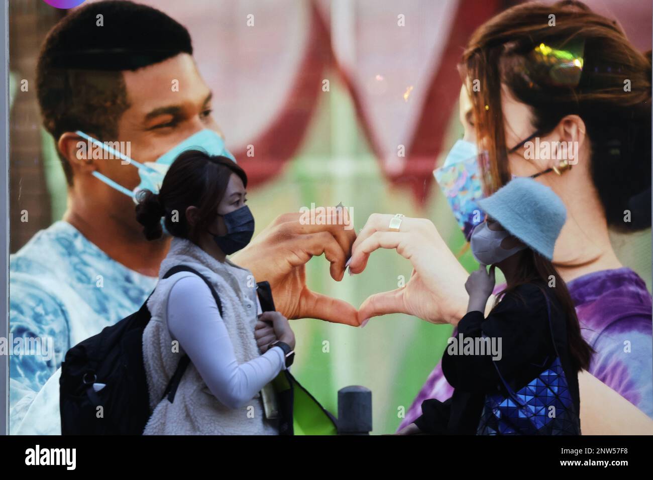 People walk past a Face masks advertisement outside a shop in Mong Kok ...