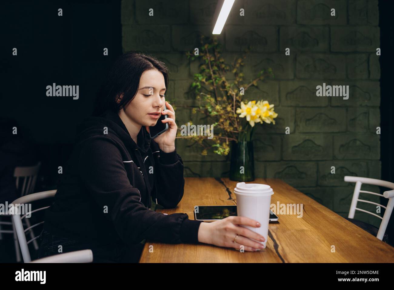 Young charming woman calling with cell telephone while sitting alone in ...