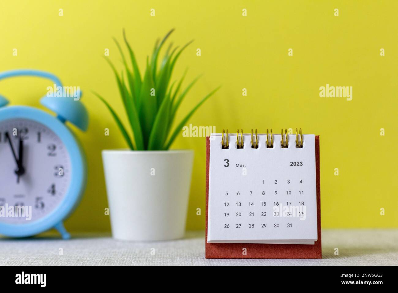 A desktop calendar for March 2023 and a clock on the table for planning ...