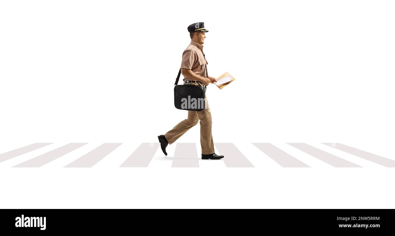 Full length profile shot of a mailman walking on a pedestrian crossing ...