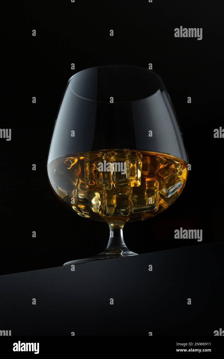 Glass of alcohol with ice seen from below on a stylish dark background ...