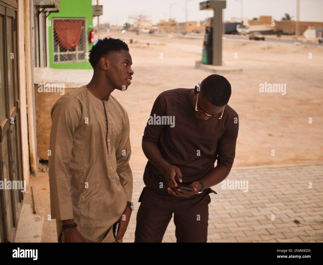 A picture of two young african men in the street. One of them lokks at ...