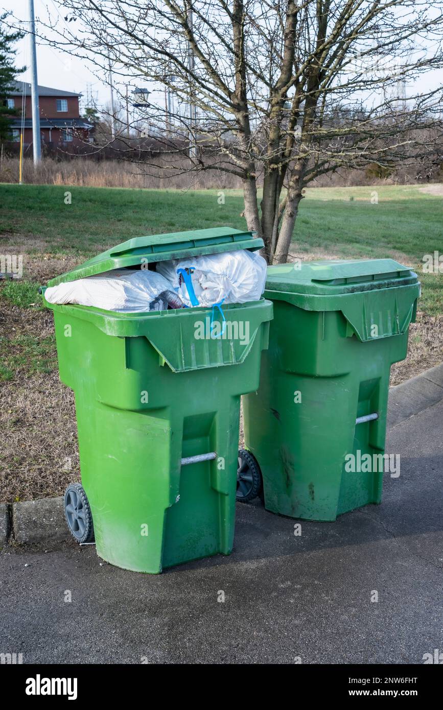 Vertical shot of two full trash containers by the curb Stock Photo - Alamy