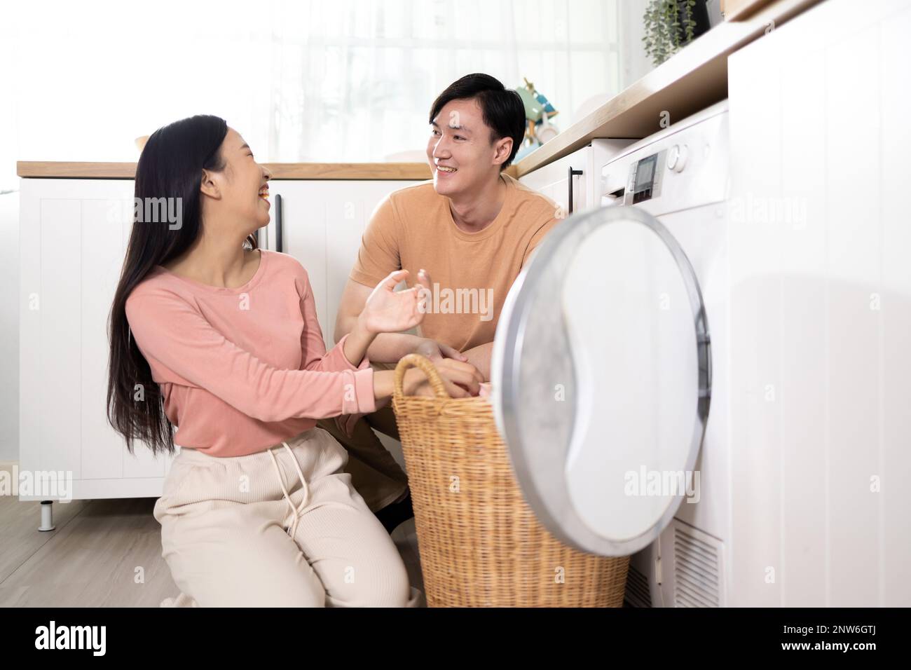 Young Asian married happy couple smiling and doing laundry at home ...
