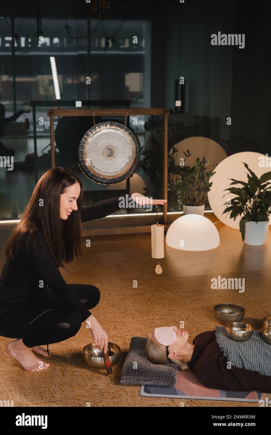 A young beautiful woman is doing a massage with singing bowls and a ...