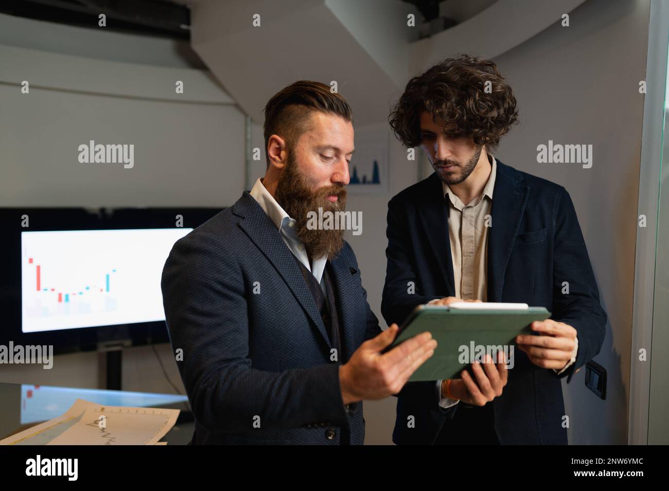 Two hipster colleagues with suits discussing about work using tablet ...