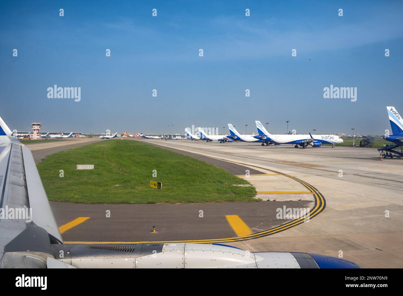 Airplanes line up in airport for departure with clear blue sky and lush ...