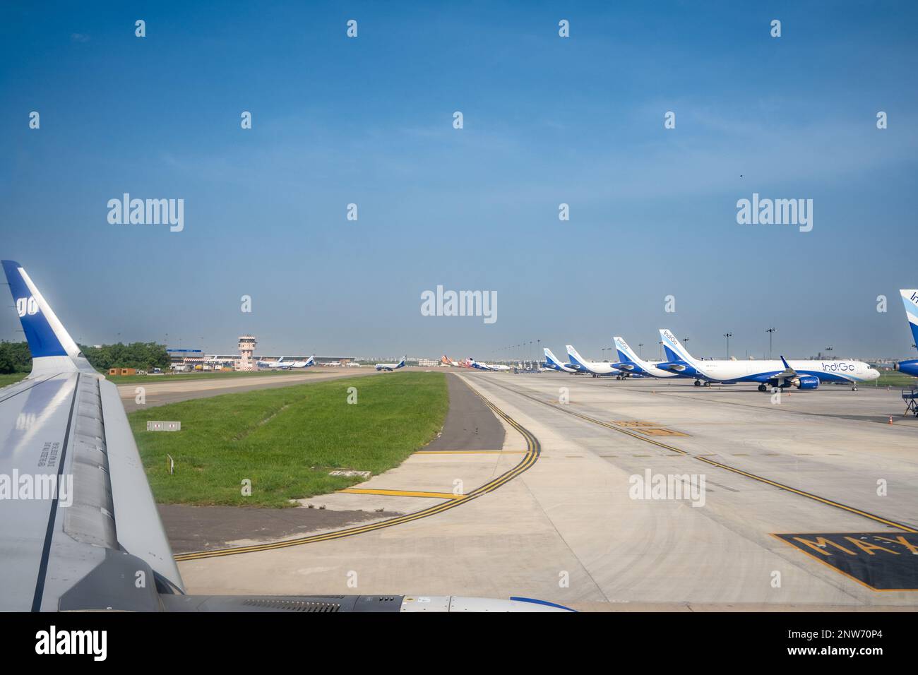 Airplanes line up in airport for departure with clear blue sky and lush ...