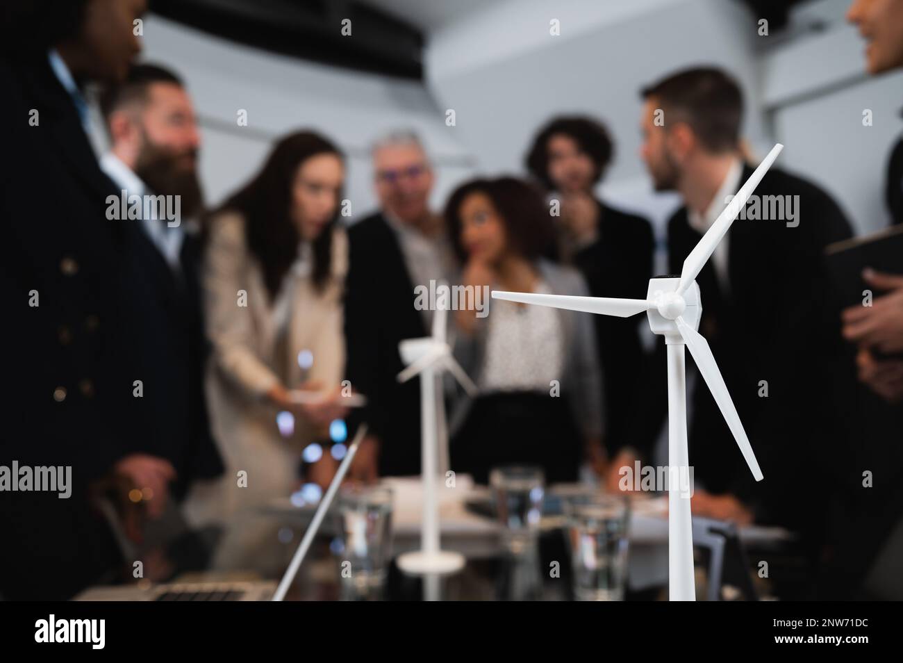 Close-up model of wind turbine. Defocused large group of engineers ...