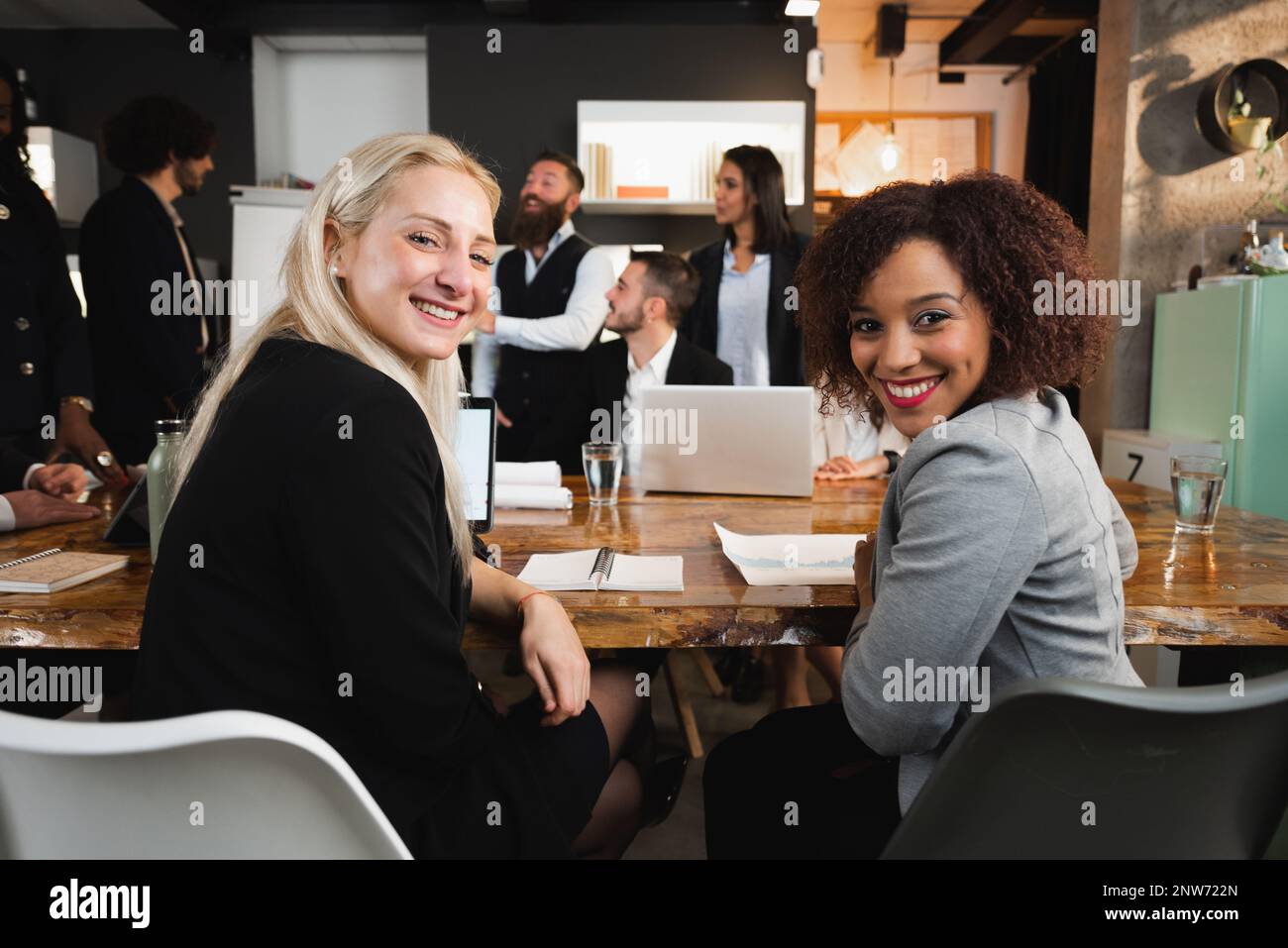 Two attractive young colleagues with different ethnicity sitting at ...