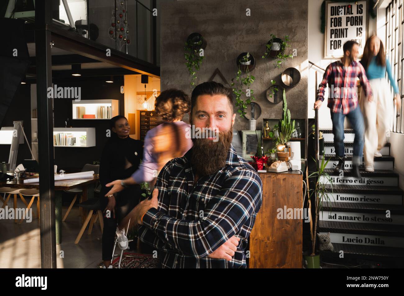 Portrait of young hipster man looking at camera with crossed arms and ...