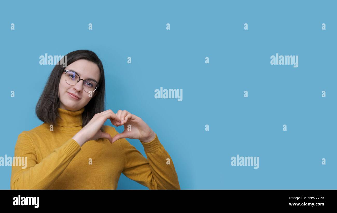 portrait beautiful student girl in glasses makes a heart shape with her ...