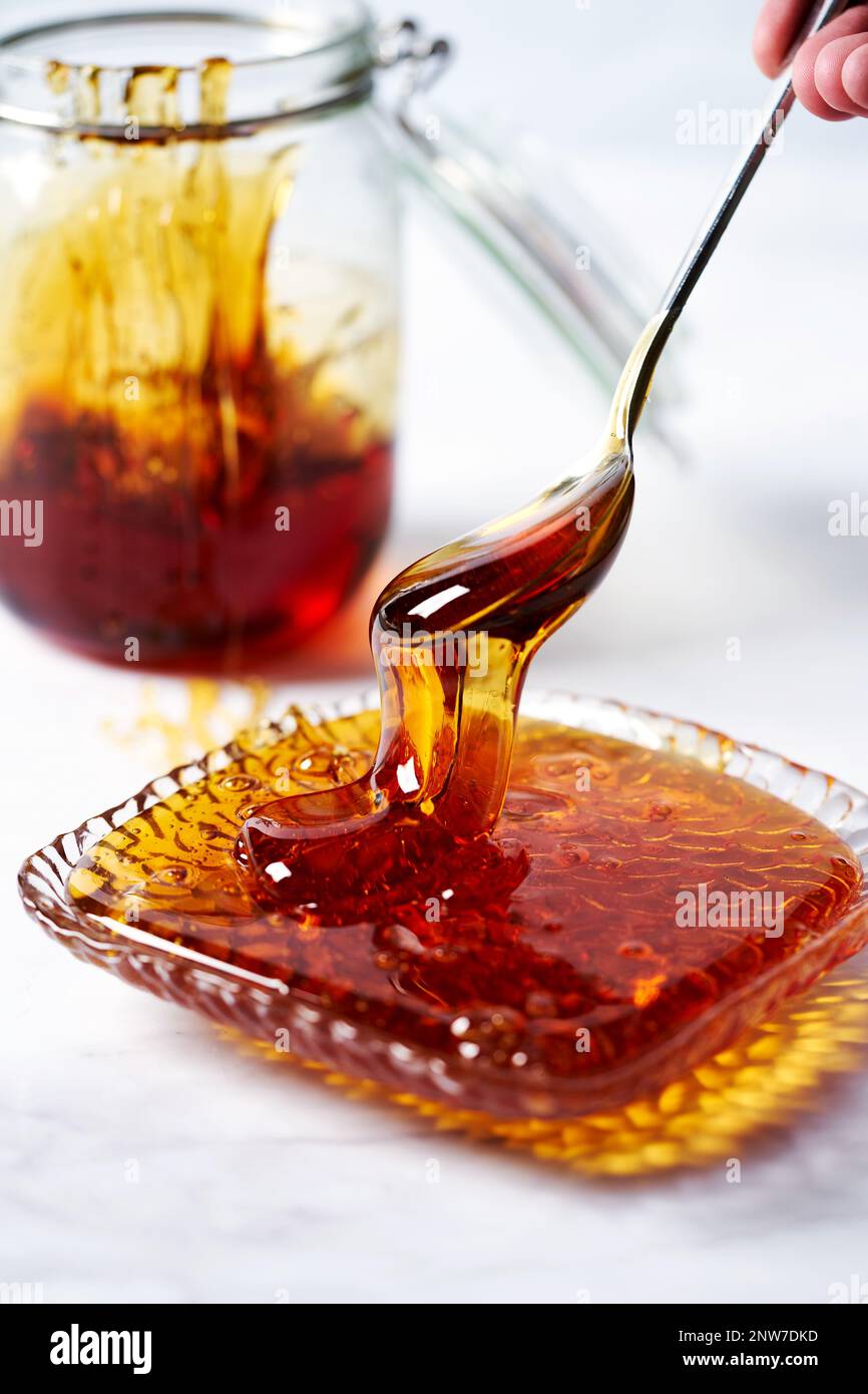 Thick golden syrup or caramel or honey dripping from the spoon into the ...