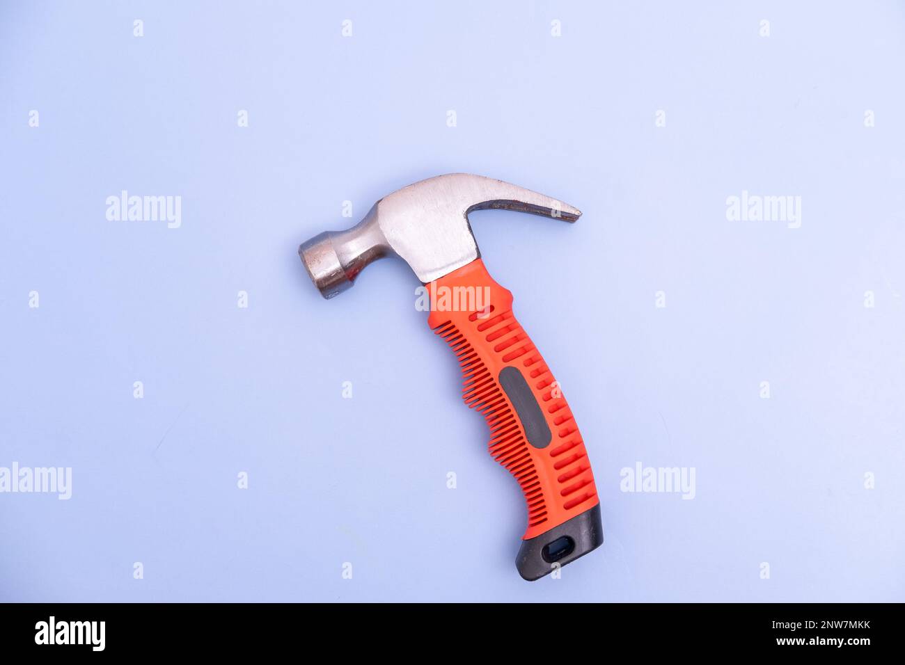 A claw hammer with a red and black handle on a lilac, blue background ...