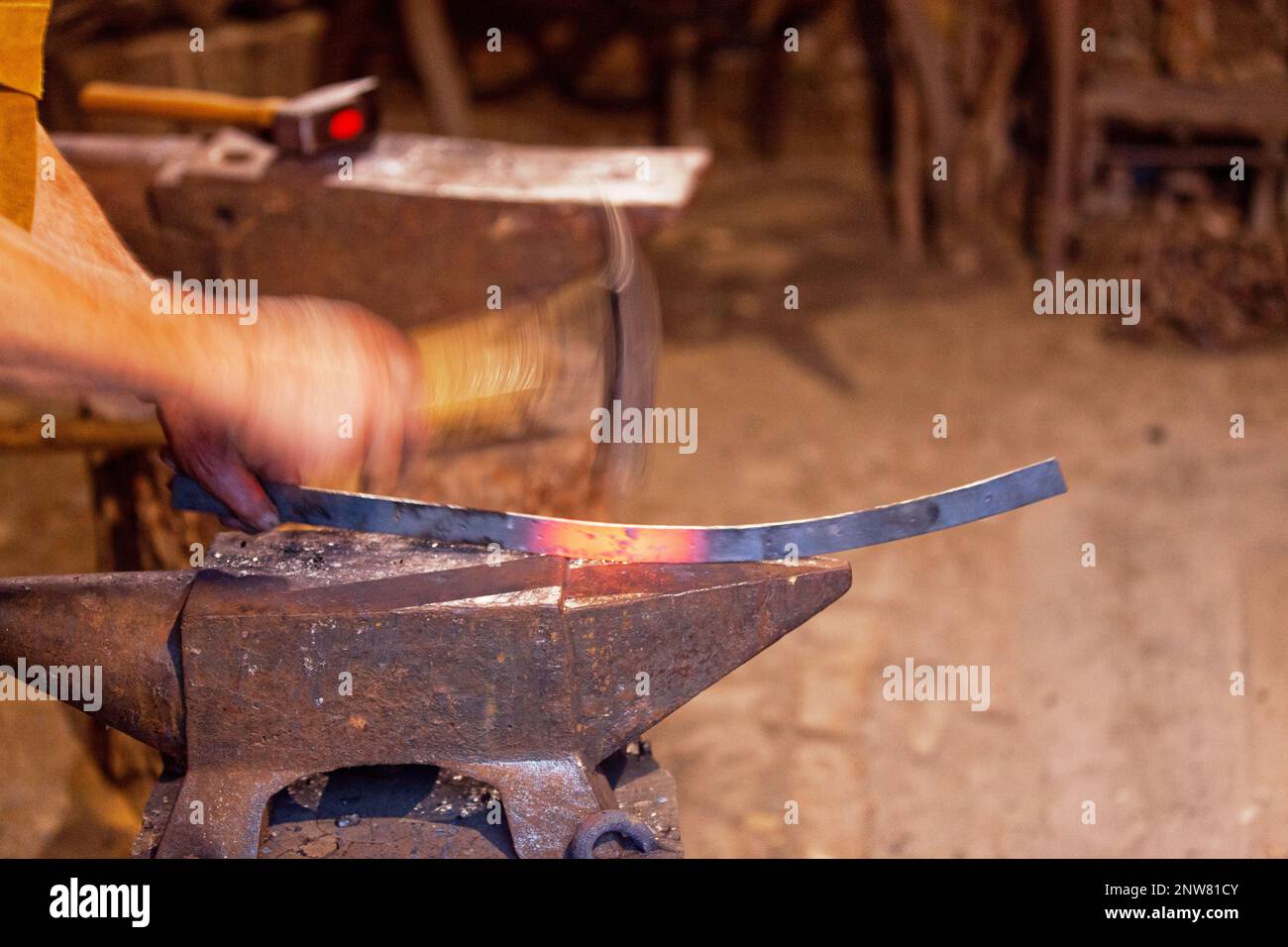 Blacksmith hammering a piece of molten iron on an anvil Stock Photo - Alamy