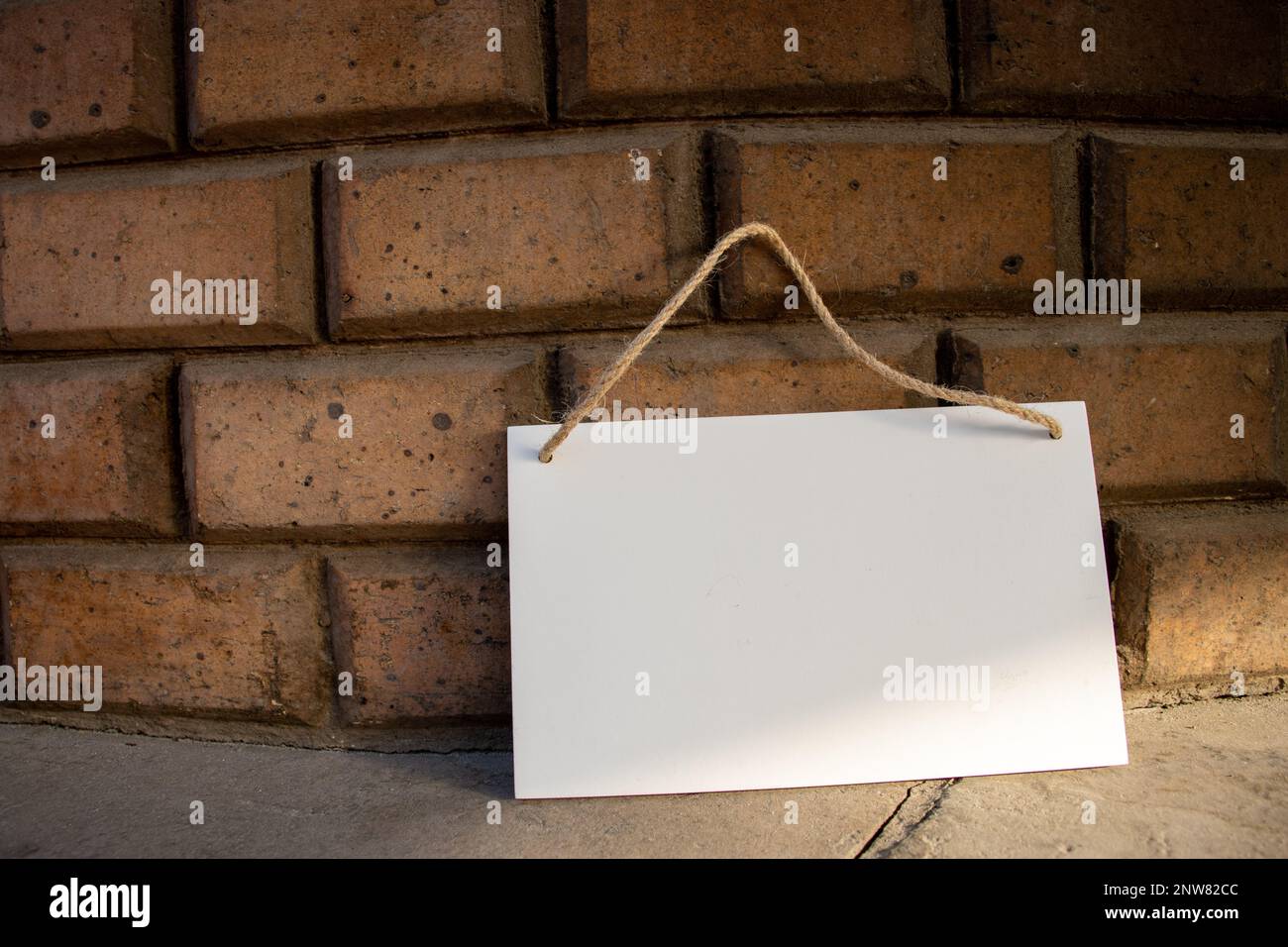 brick background white hanging picture sign with empty free space for ...