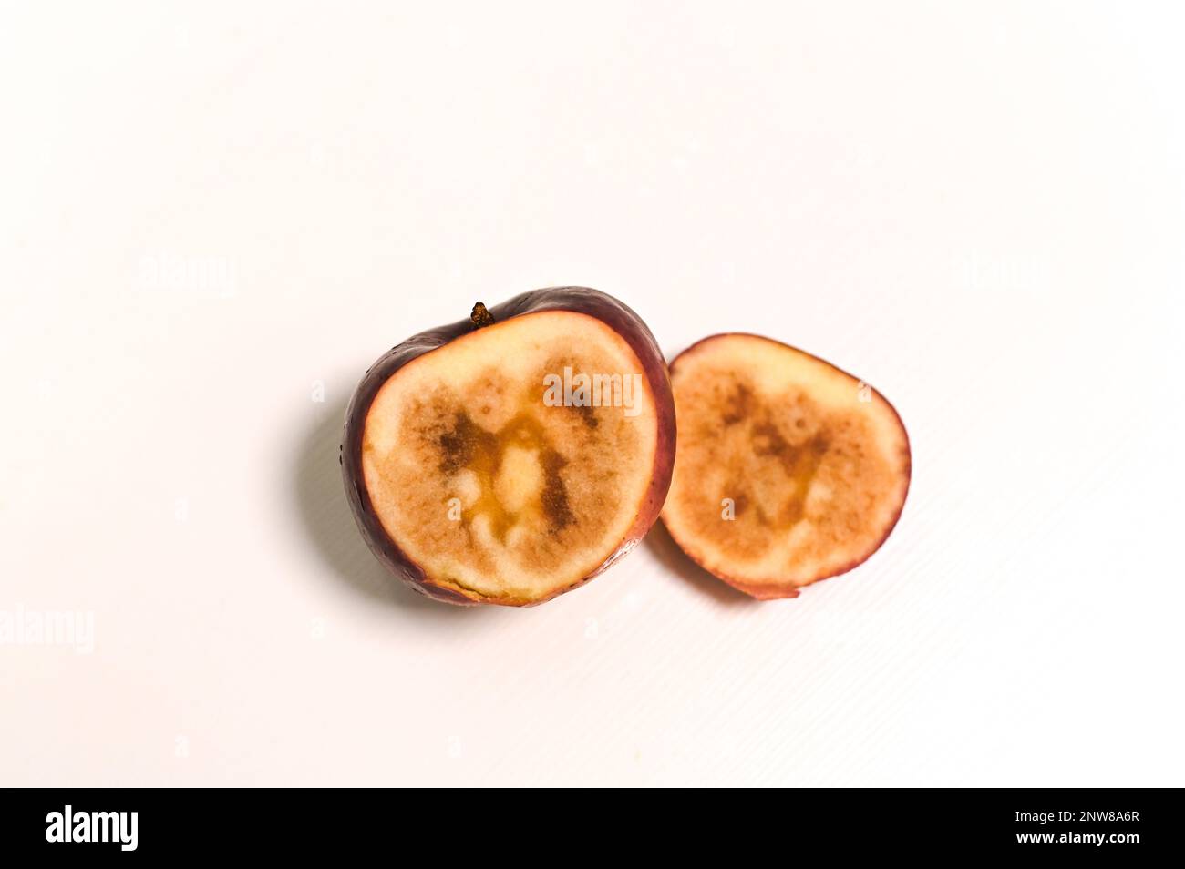a rotten apple in the cut. half a rotten apple. close-up. on a white ...
