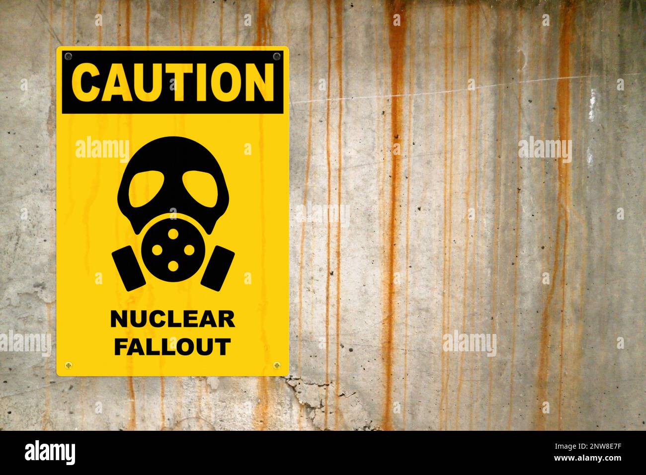 Yellow warning sign screwed to a concrete wall to warn about a threat ...