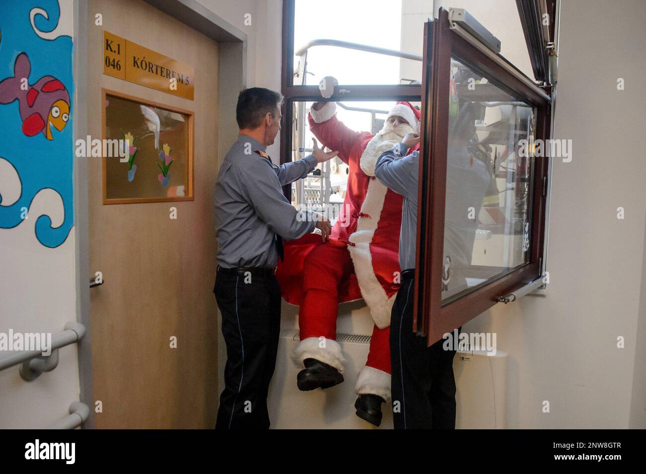 A firefighter dressed as Santa Claus enters through a window into a ...