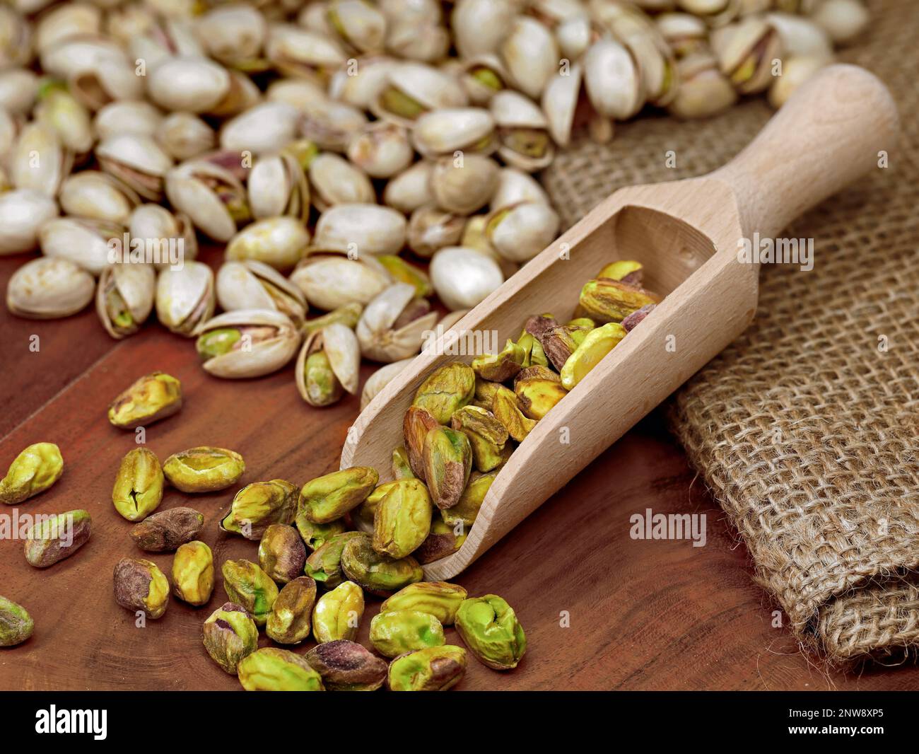 organic pistachios without shell in wooden scoop on wooden table next ...