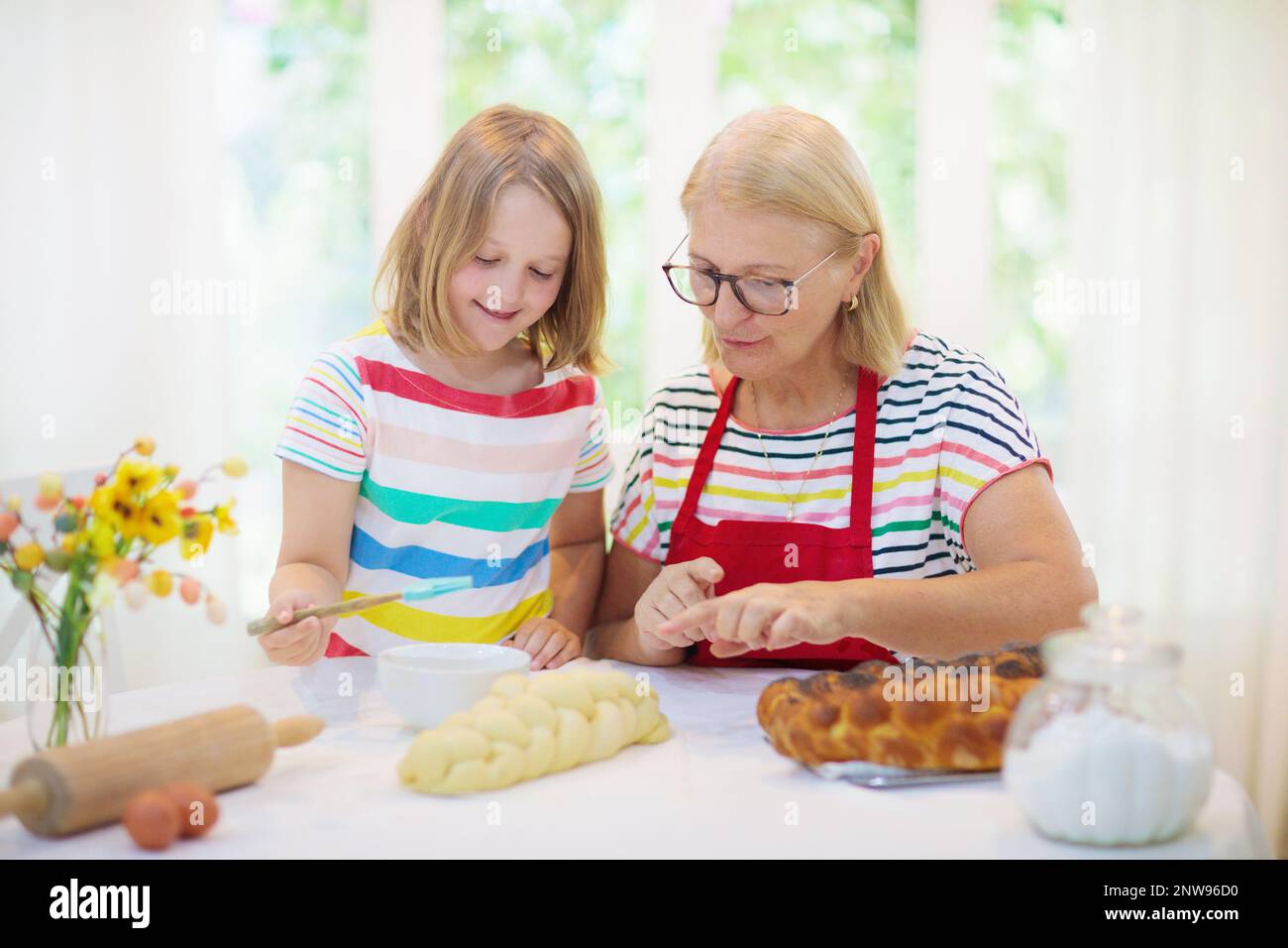 Mom and child baking bread. Grandmother and little girl bake challah ...