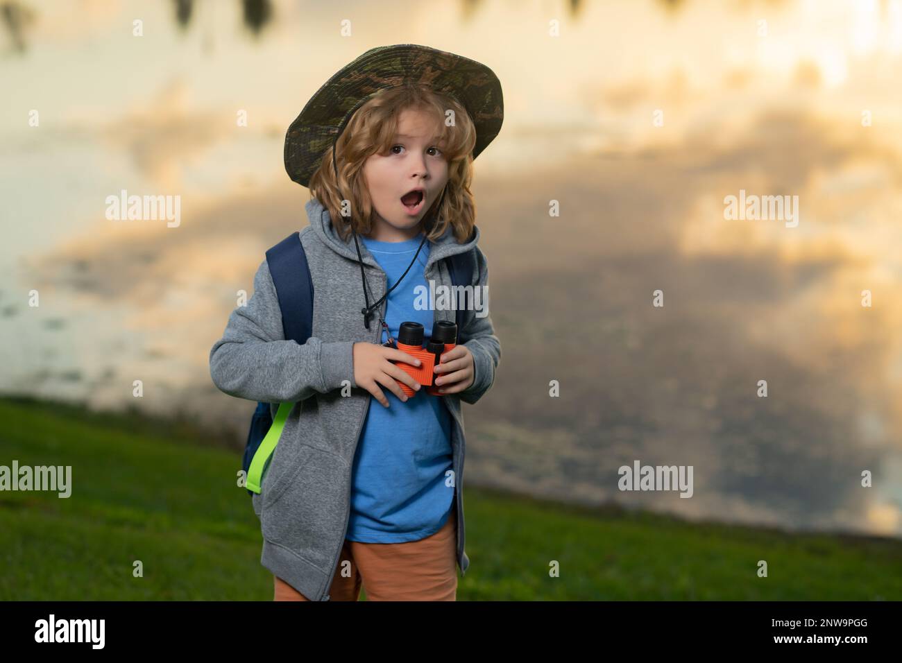 Dreams of discoveries. Cute blond kid with binoculars wearing explorer ...