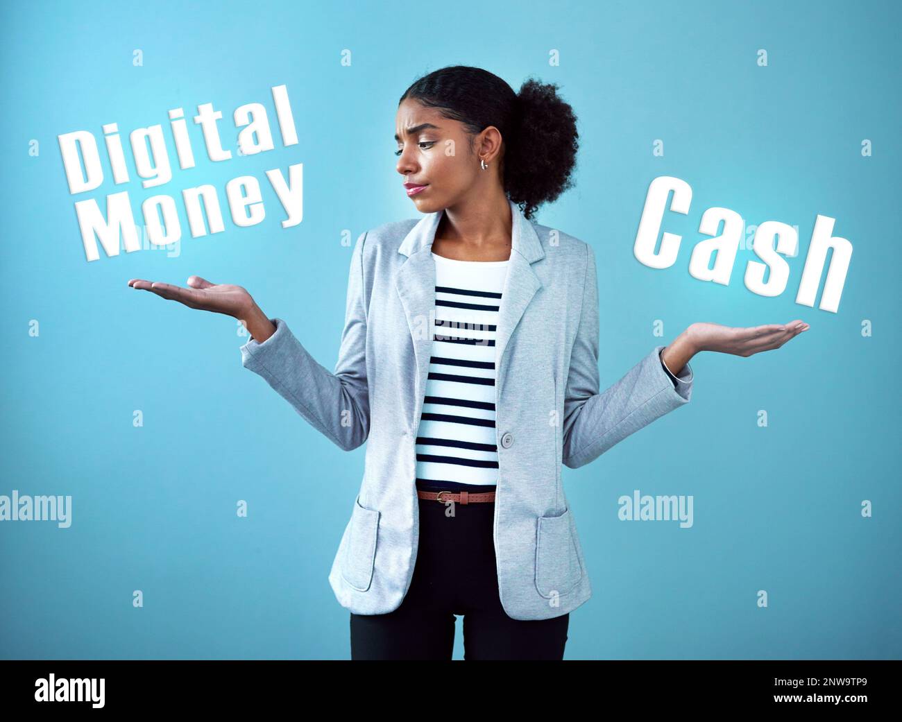 The currency of the future. Studio shot of an attractive young woman weighing up her monetary ...