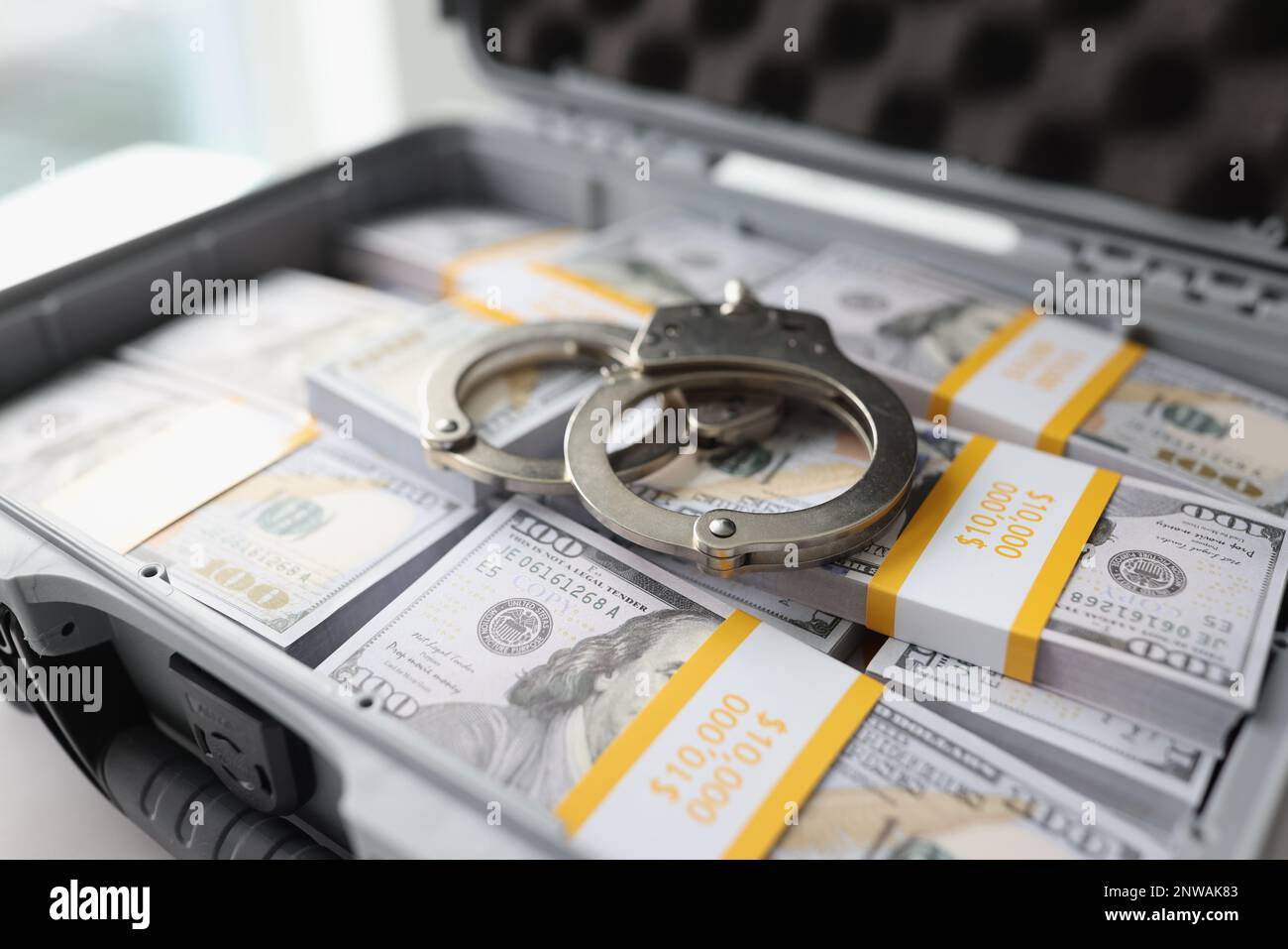Handcuffs on pile of cash in suitcase Stock Photo - Alamy