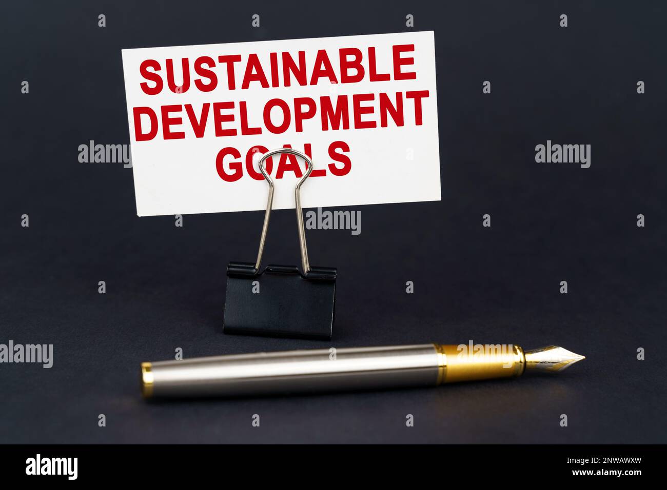 Business concept. On the black surface is a pen, an office paper clip ...