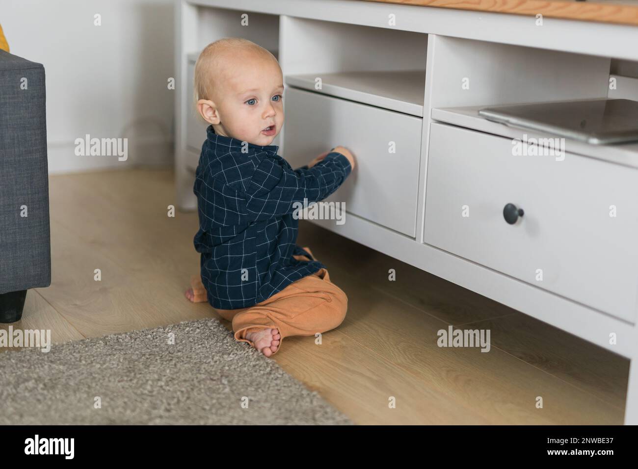 Toddler baby boy open cabinet drawer with his hand. Child explore what ...