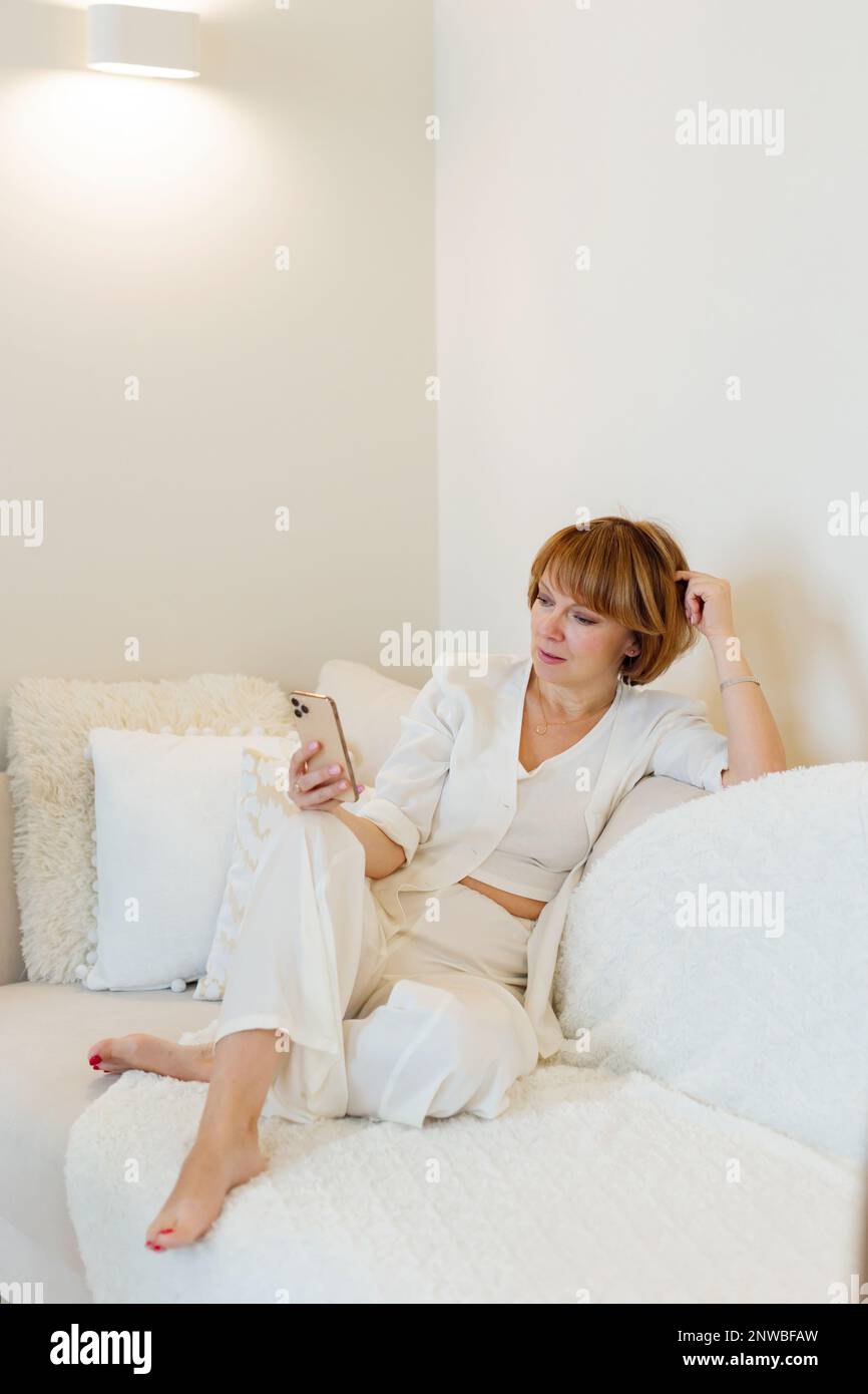 Adult Beautiful Woman Relax Siting On Sofa At Home And Using Cellphone